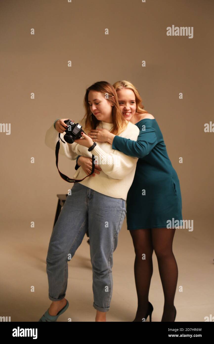 Two girls hug in a photo Studio. The photographer look at the pictures ...