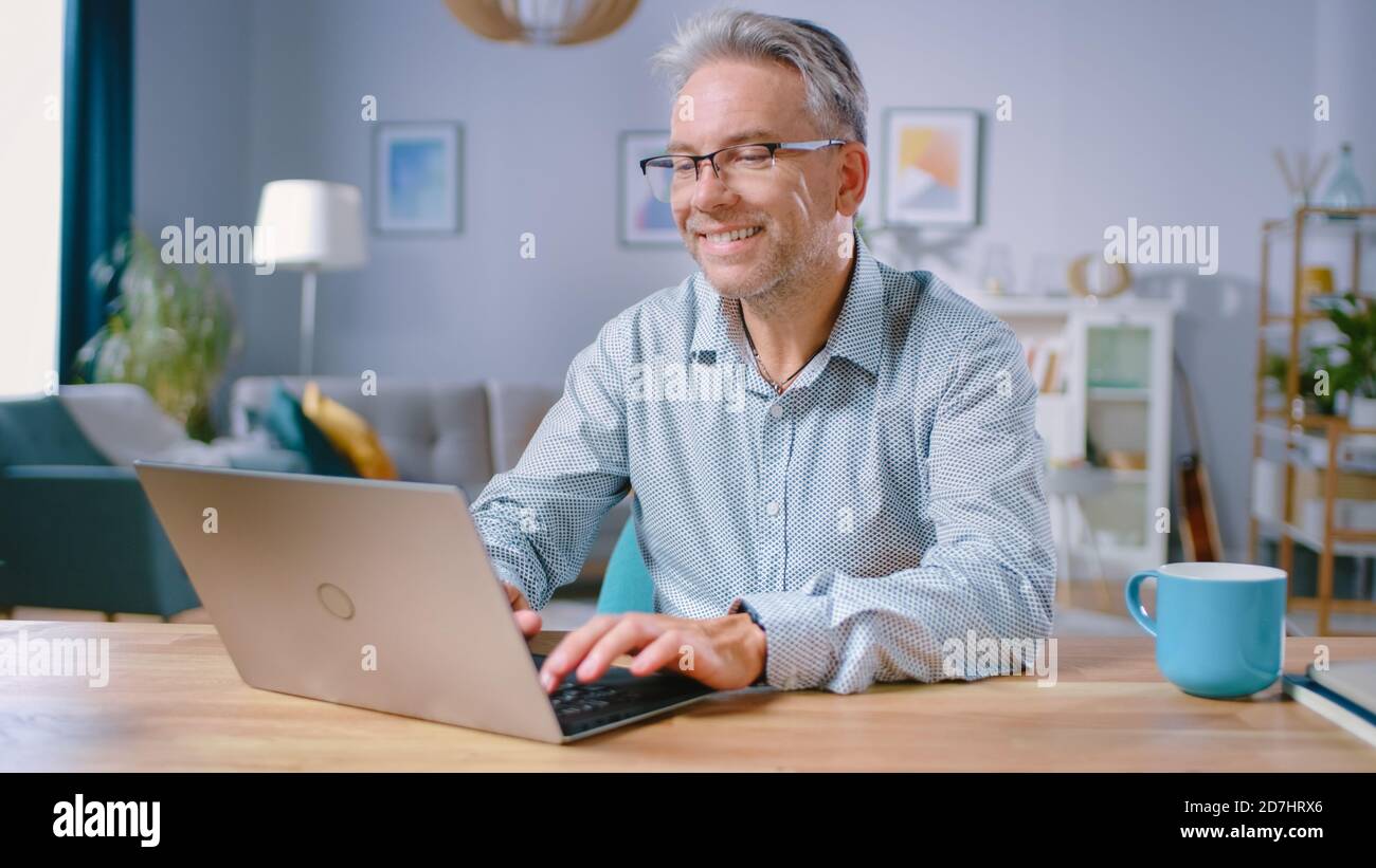 Handsome Middle Aged Man Uses Laptop Computer While Sitting at His Desk ...