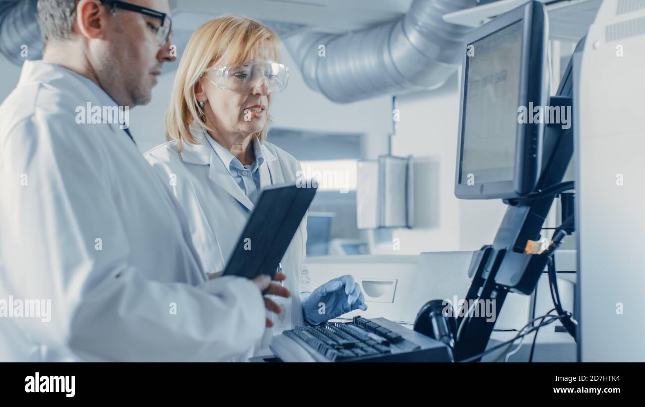 Two Research Scientists Programm Medical Equipment with Tablet Computer. Team of Professionals ...
