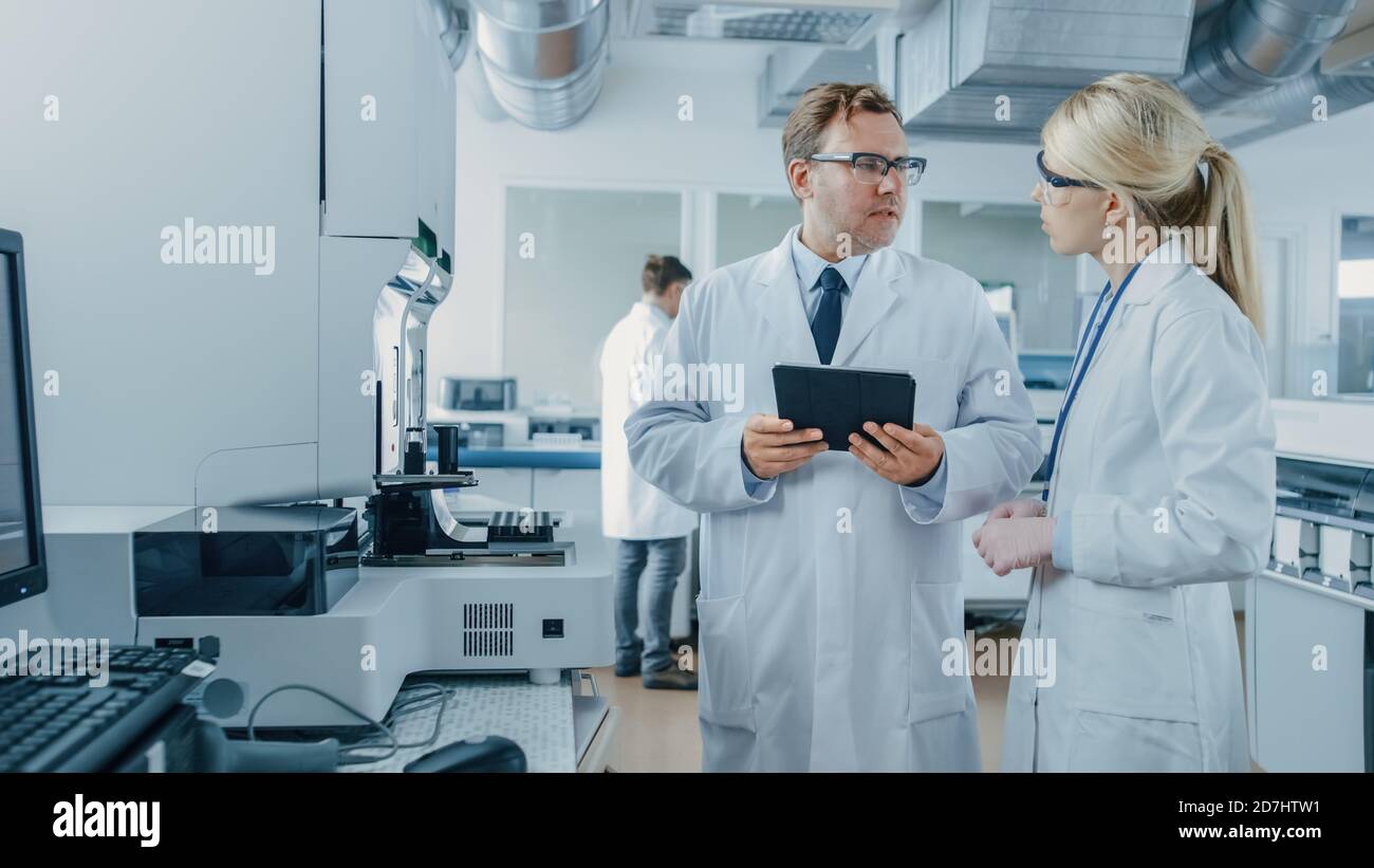 Male and Female Research Scientists Talking, Using Digital Tablet ... Male and Female Research Scientists Talking, Using Digital Tablet ...