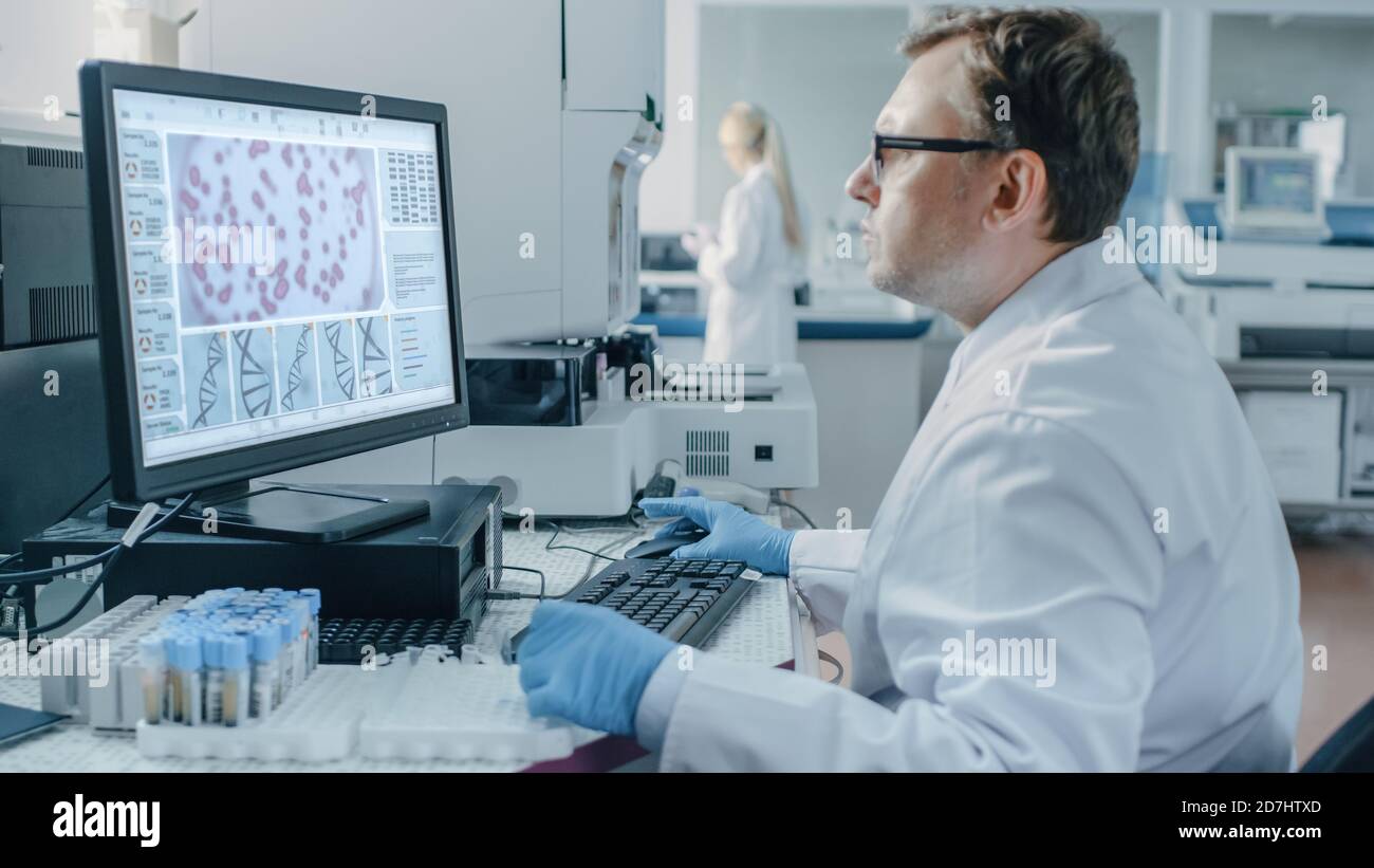 Male Scientist Sits at His Workplace in Laboratory, Uses Personal ...