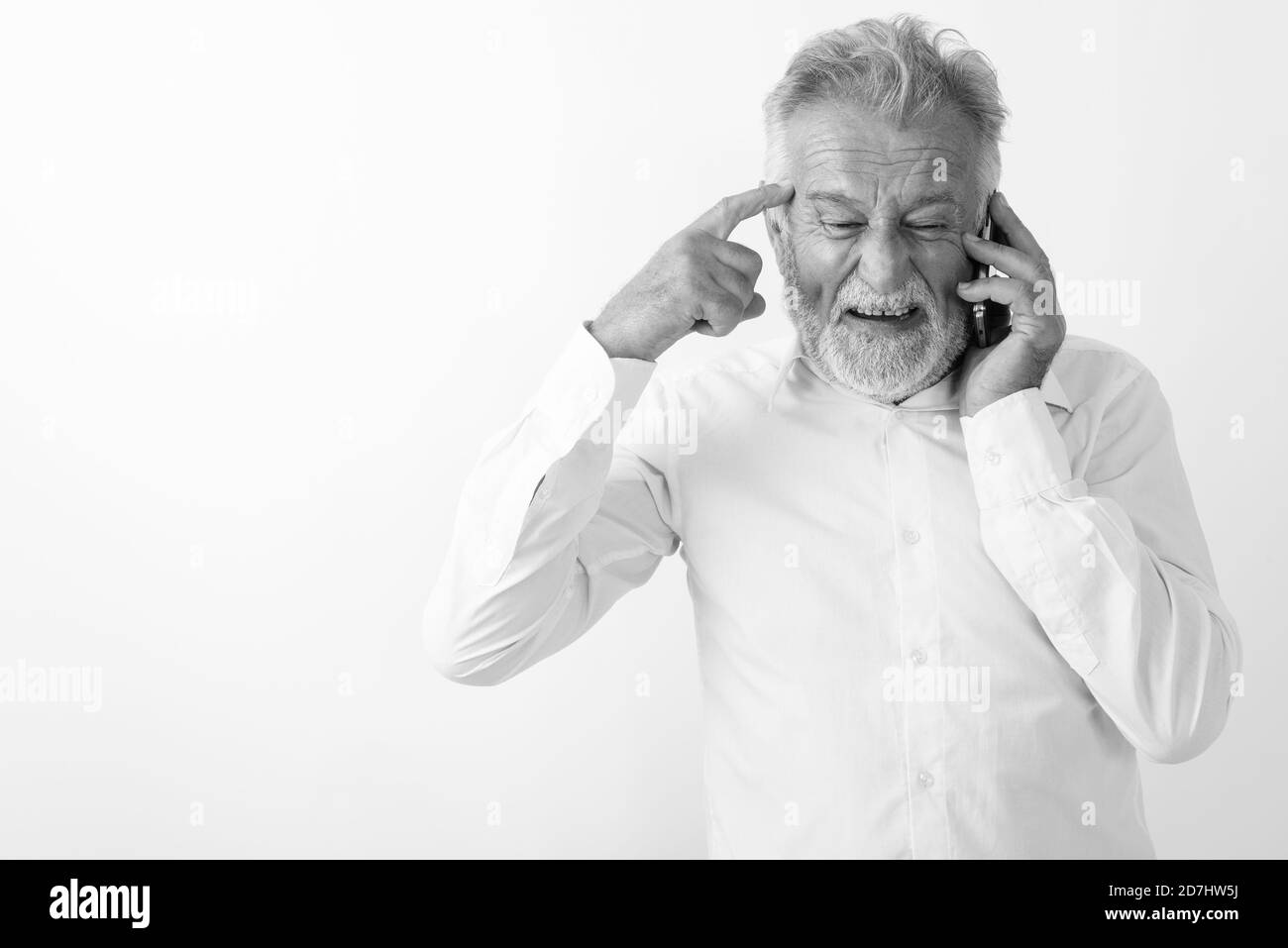 Studio shot of angry senior bearded man thinking while talking on ...