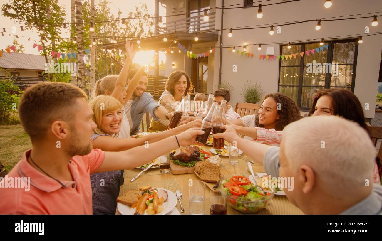 Family and Friends Gathered Together at the Table Raise Glasses and ...
