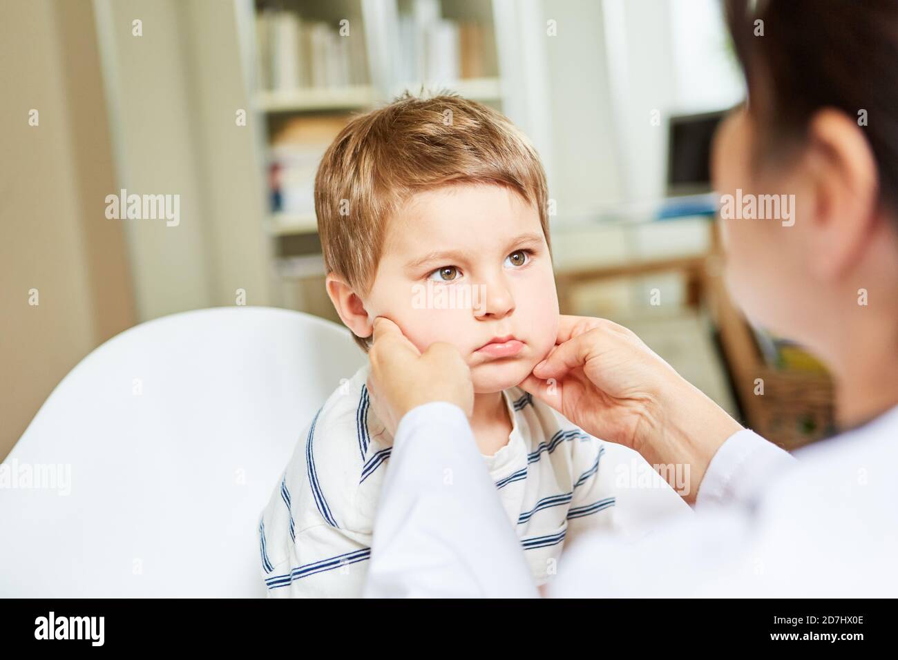 Pediatrician palms the tonsils and swollen lymph nodes in a child with ...