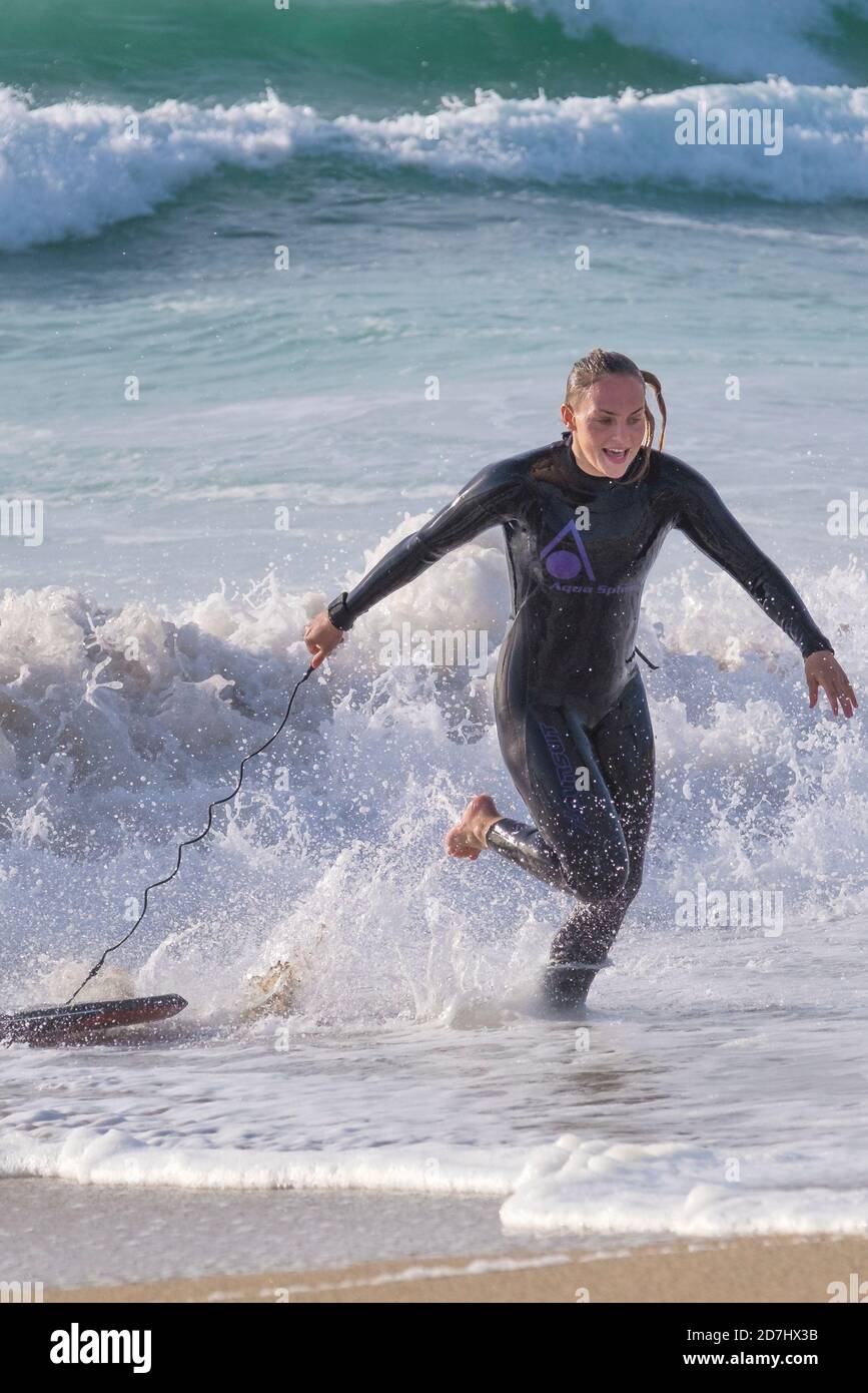 A female holidaymaker pulling her bodyboard and having fun running out ...