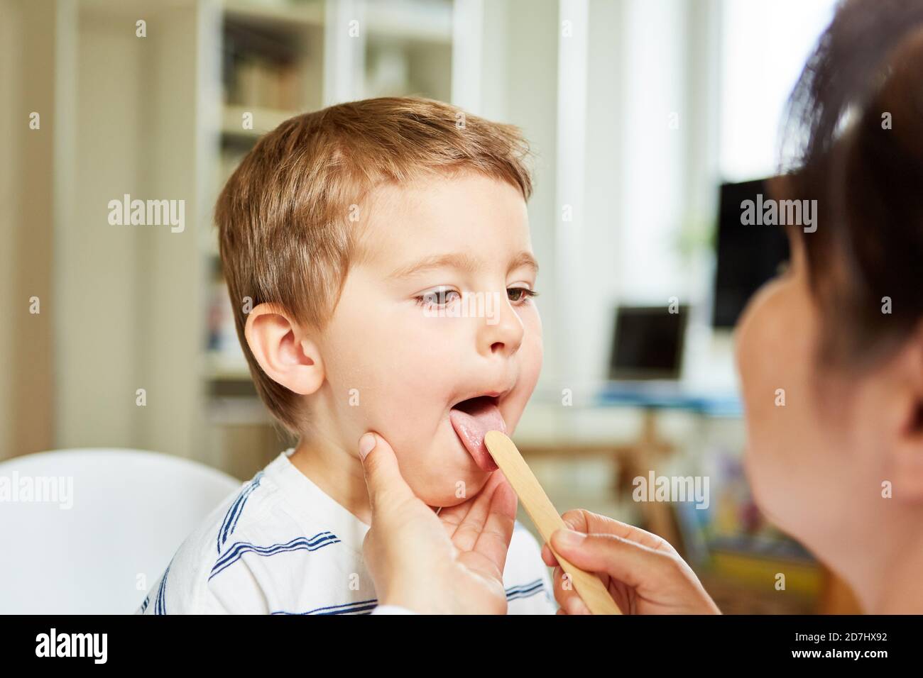 Pediatrician examines tongue of a child with tonsillitis with a spatula ...