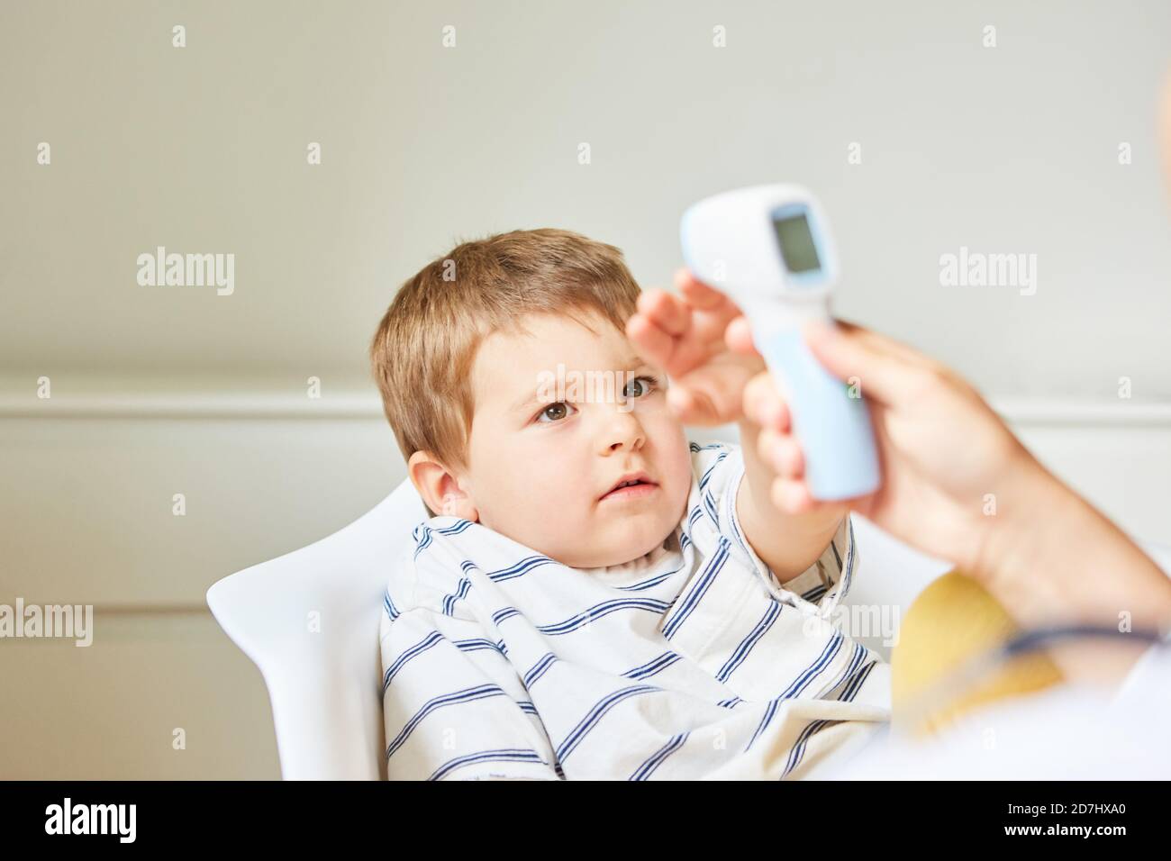 An anxious child with the flu or a cold while measuring a fever with ...