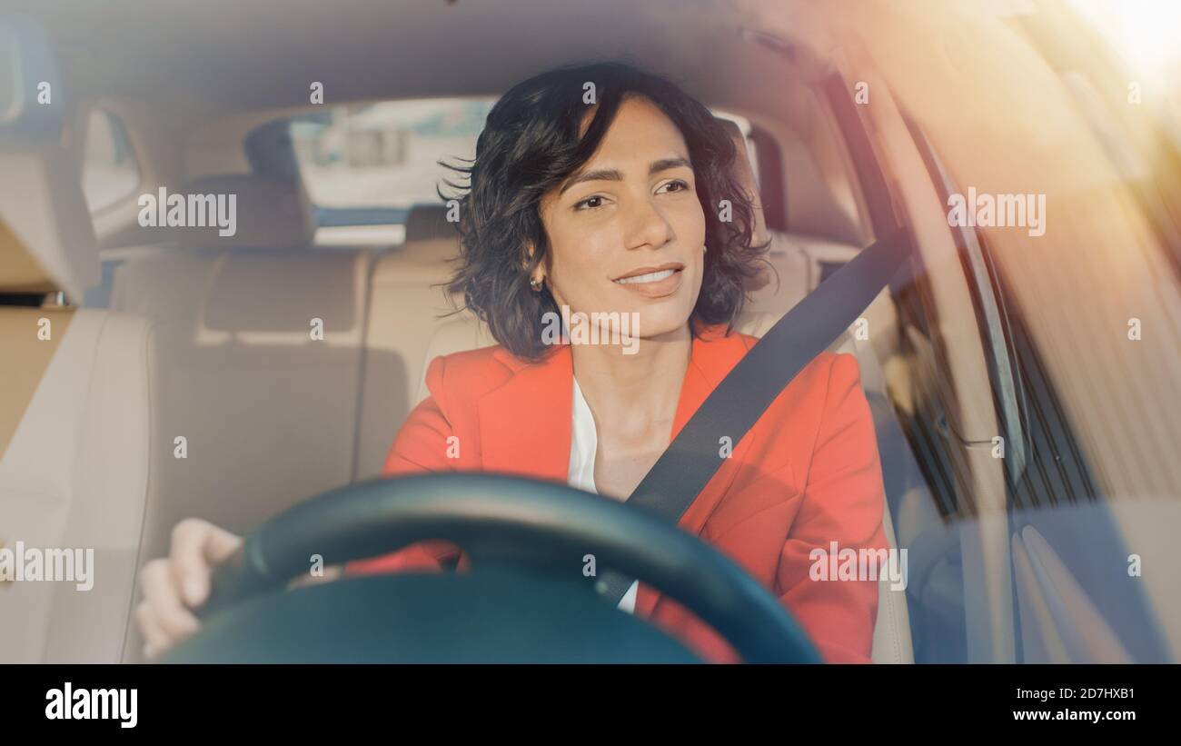 Portrait of beautiful Young Woman Driving Car through big Sunny City ...