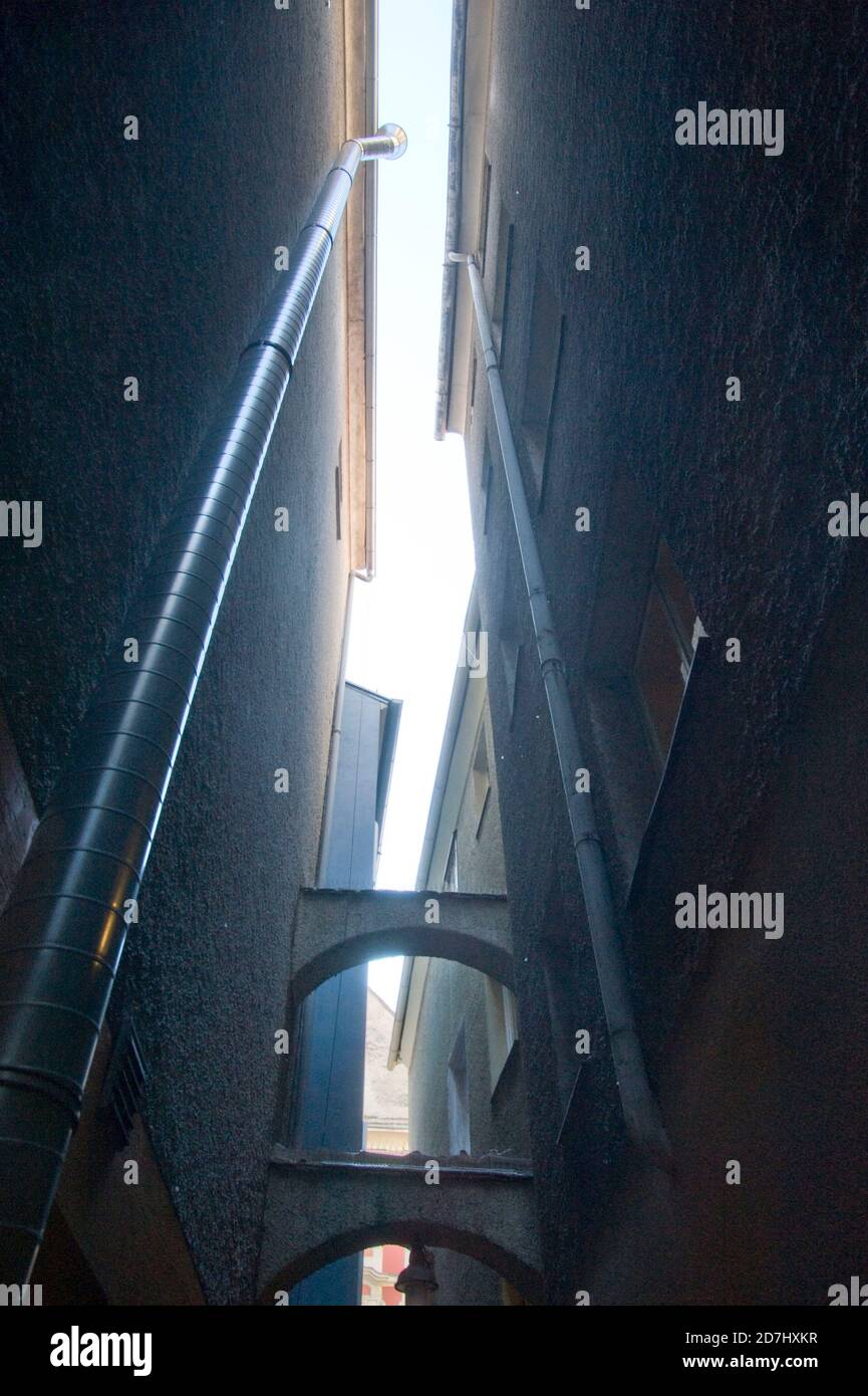 atrium, narrow dark lane with light from above between two buildings ...