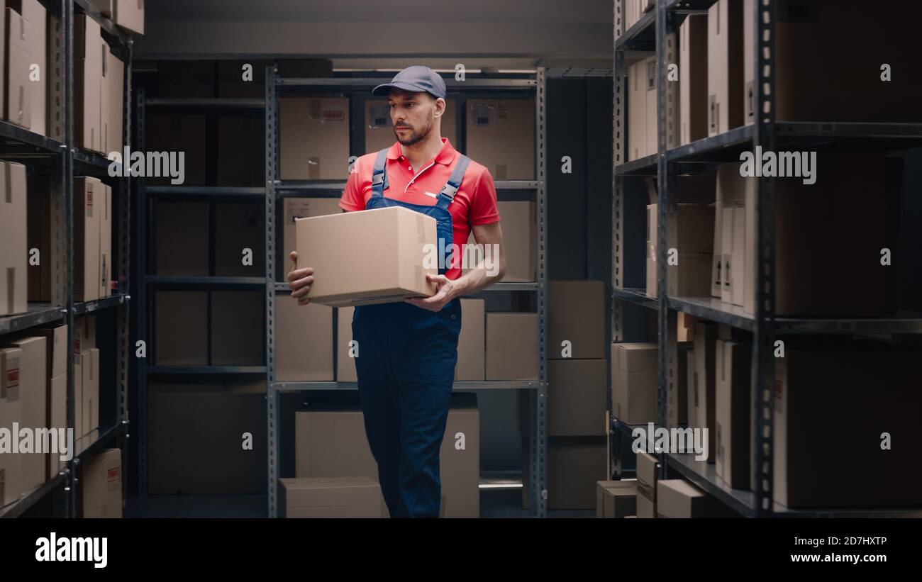 Handsome Warehouse Worker Walks in Storeroom with a Cardboard Box Stock ...