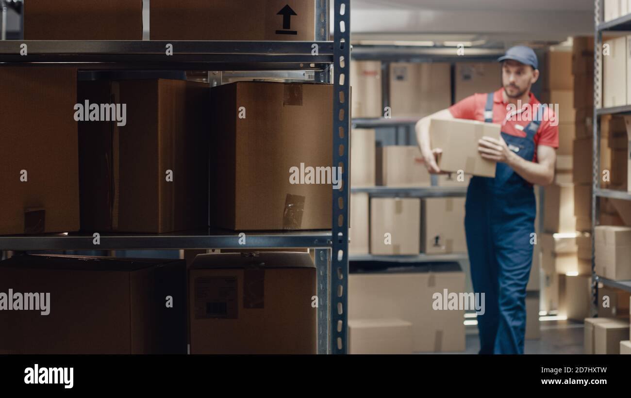 Handsome Warehouse Worker Walks into Storeroom with a Cardboard Box ...