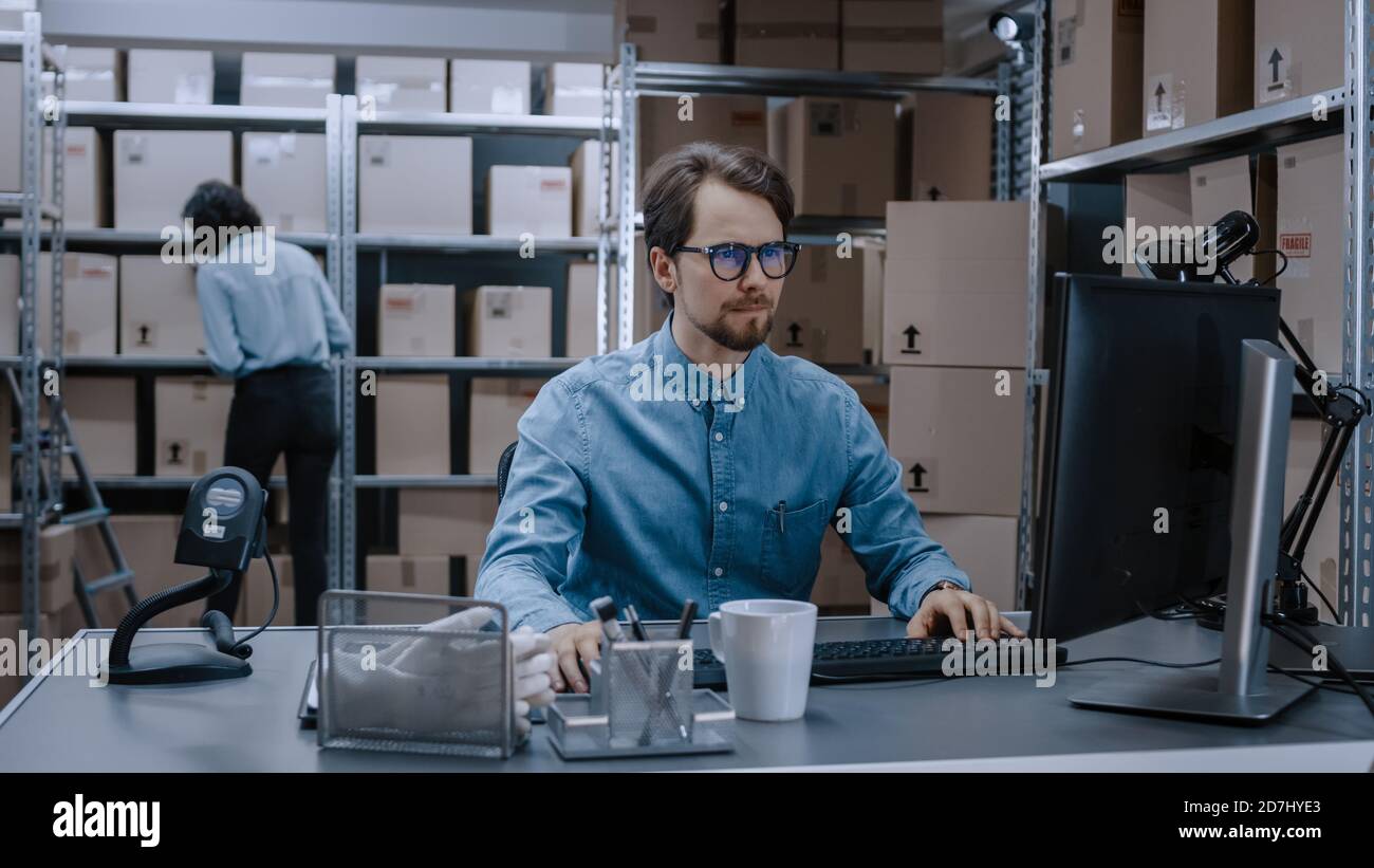Warehouse Inventory Manager Works on Computer while Sitting at His Desk ...