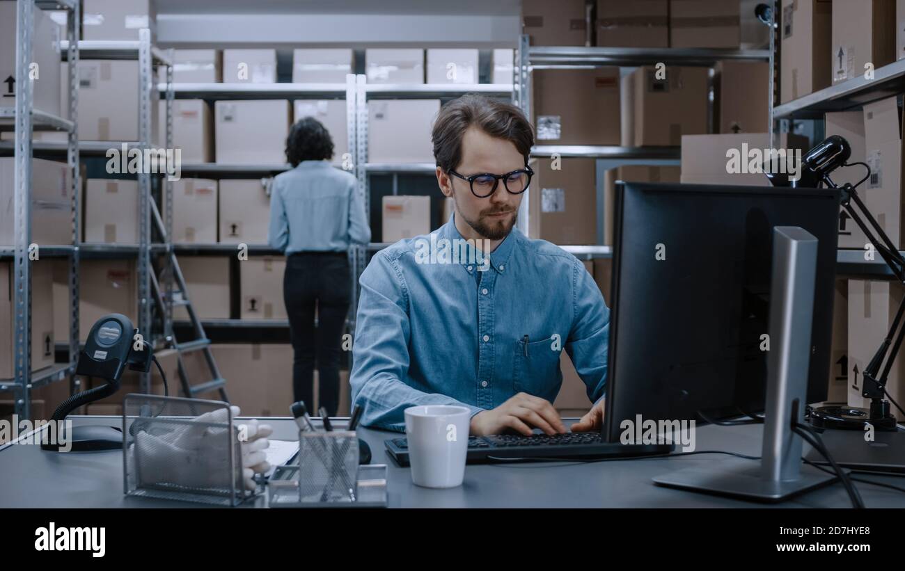 Warehouse Inventory Manager Works on Computer while Sitting at His Desk ...