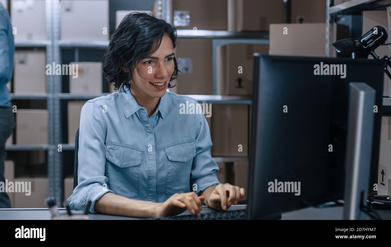 Warehouse Female Inventory Manager Works on a Computer while Sitting at ...
