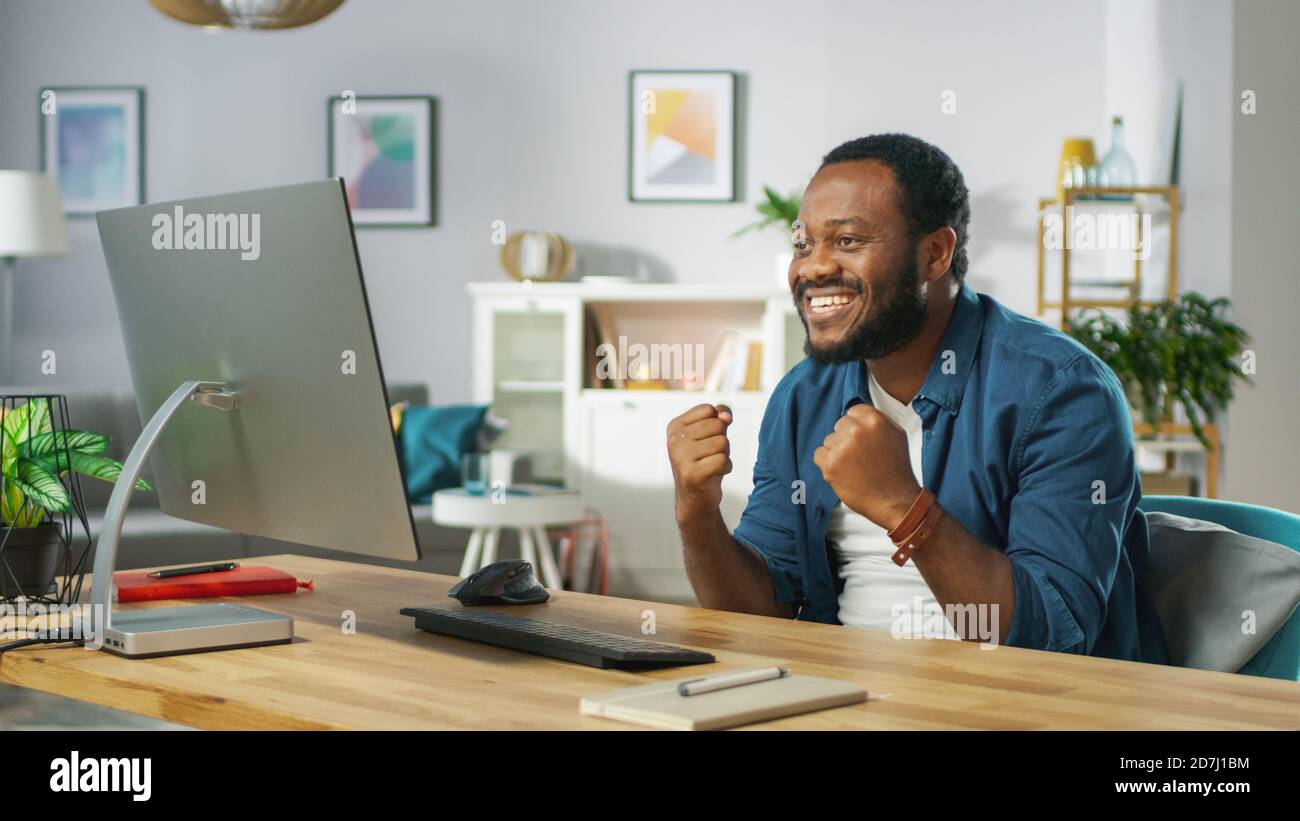 Excited Young Man Uses Personal Computer at Home, Wins Big, Does "Yes ...