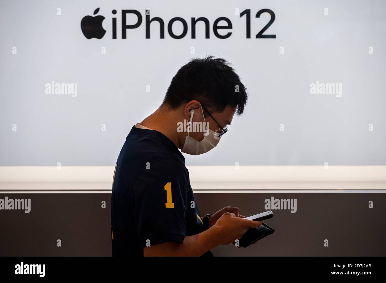 A customer queues in line at an Apple store during the launch day of ...