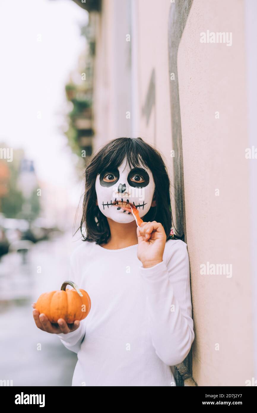 Girl with face paint, eating Halloween candy Stock Photo - Alamy