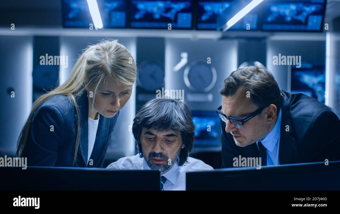 Male and Female Operators Working On Computers in System Control Room ...