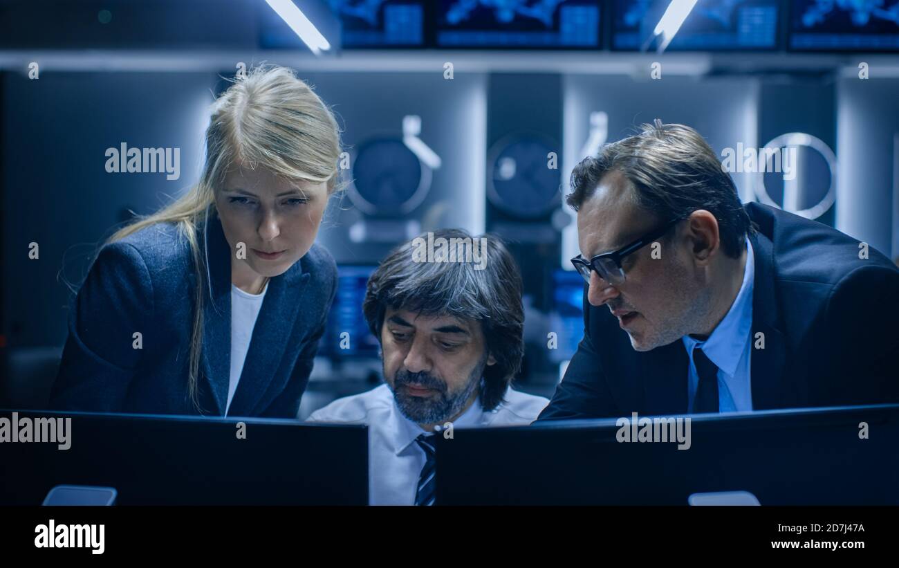 Male and Female Operators Working On Computers in System Control Room ...