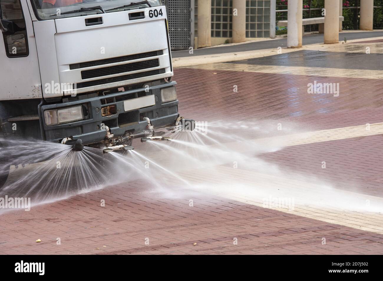 Truck cleaning a village square with water jets at the front spraying ...