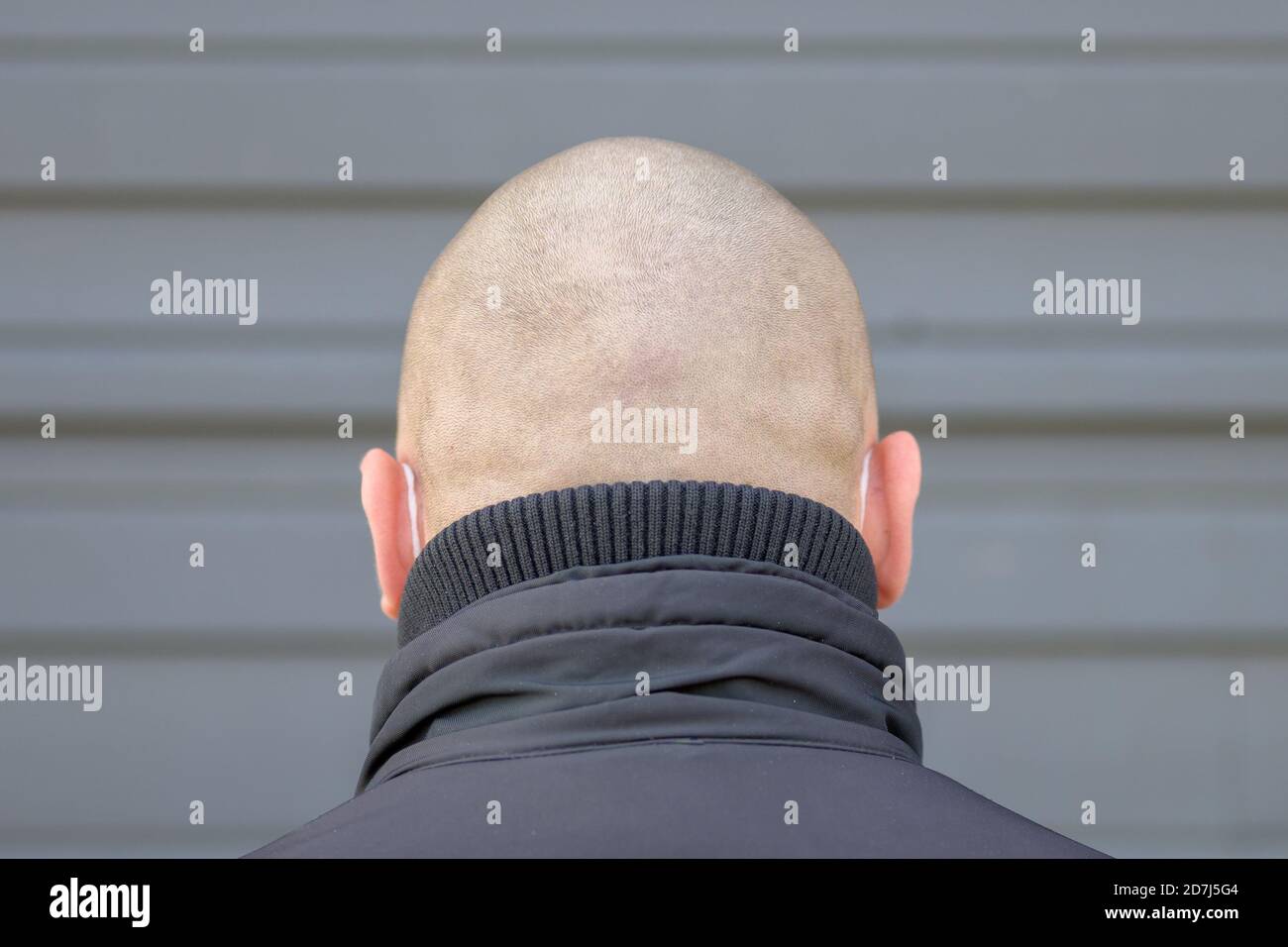Rear view of the shaved head of a man wearing a casual black top with ...