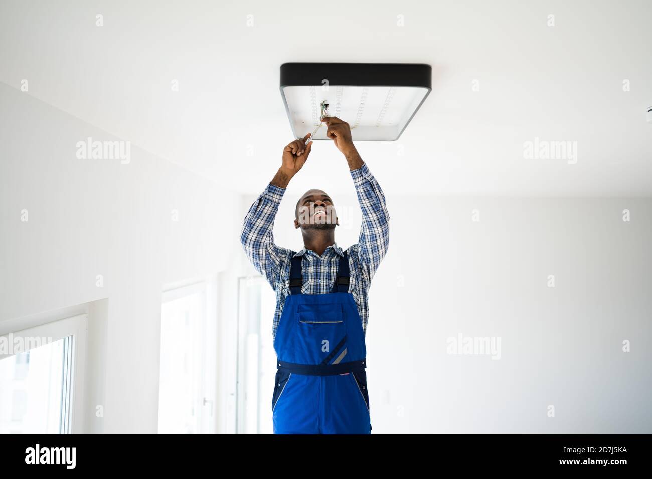 African Maintenance Electrician On Ladder Fixing And Installing Light ...