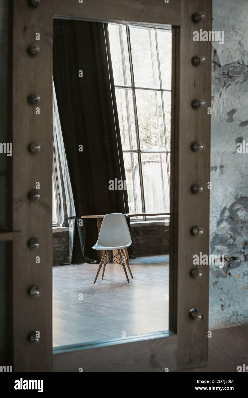 White table or armchair is reflected in large floor mirror in studio ...