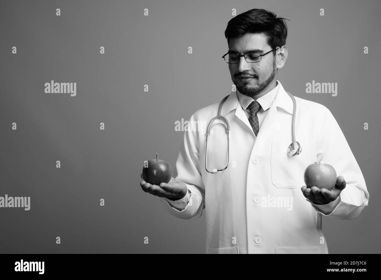 Young handsome bearded Persian man doctor against gray background Stock ...