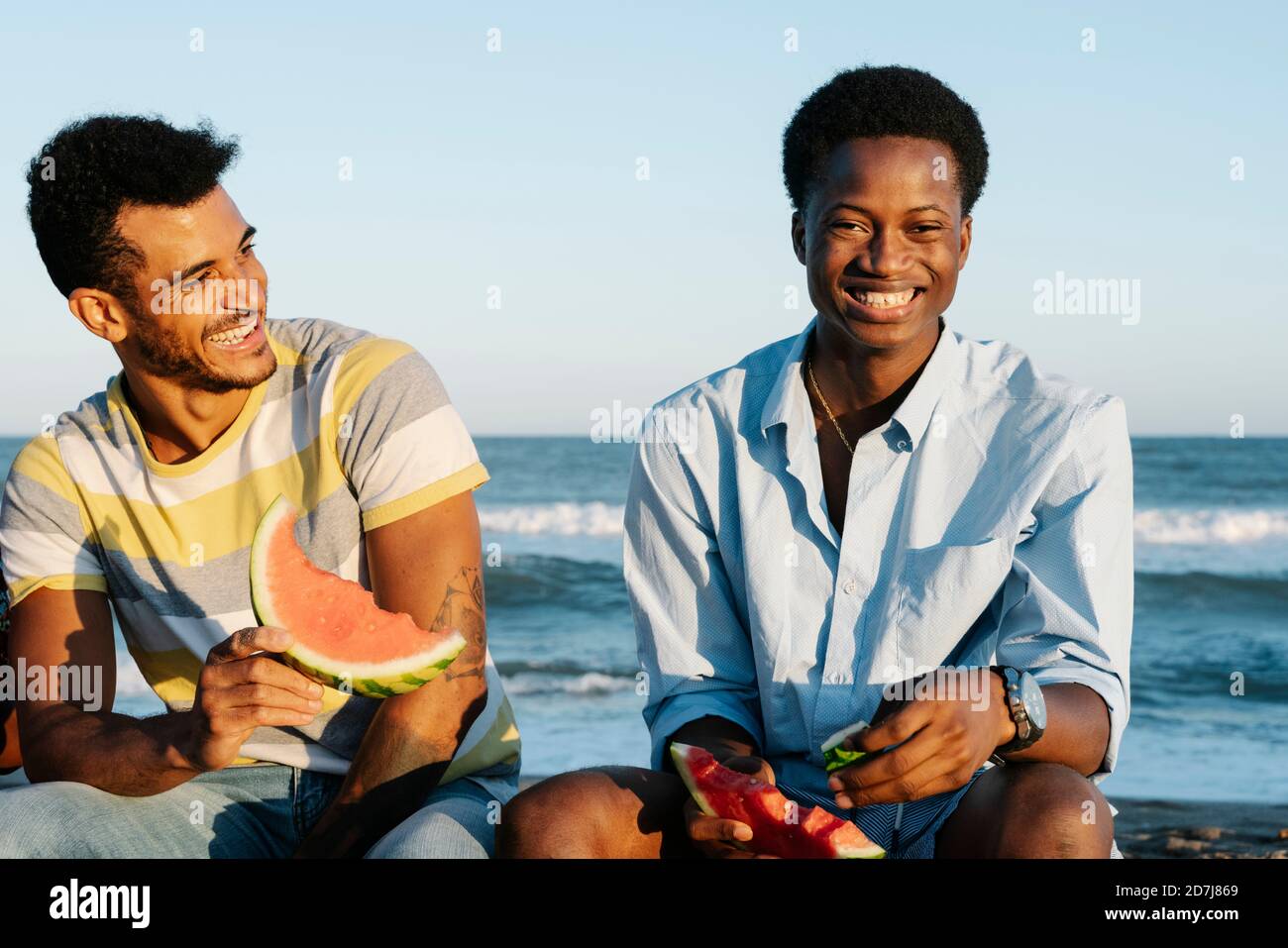 Friends laughing while eating watermelon on sunny day Stock Photo - Alamy
