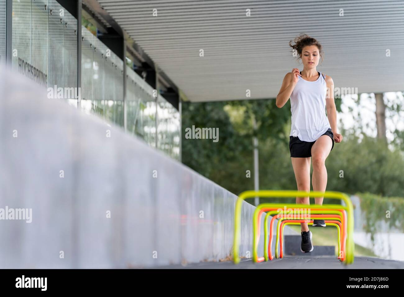 Serious female athlete running over small hurdles Stock Photo - Alamy