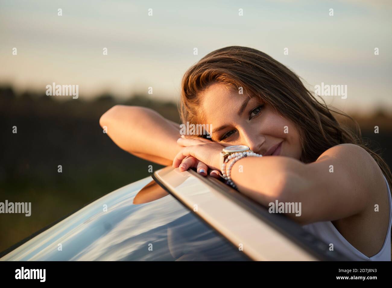 Beautiful woman leaning on car front Stock Photo - Alamy