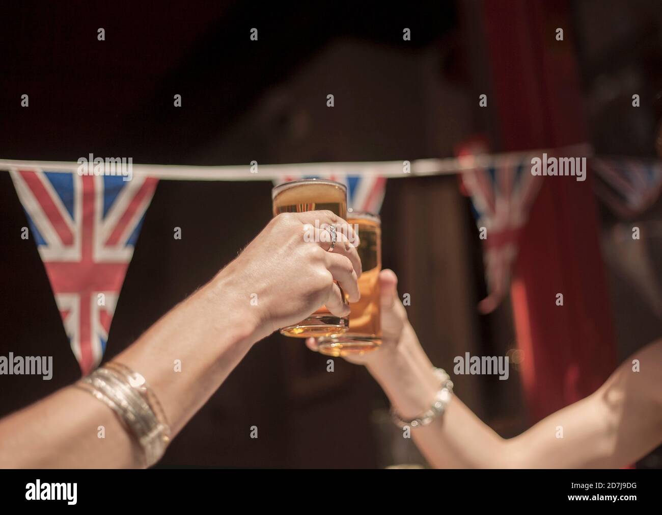 Female friends toasting beer glasses while enjoying weekend at pub ...