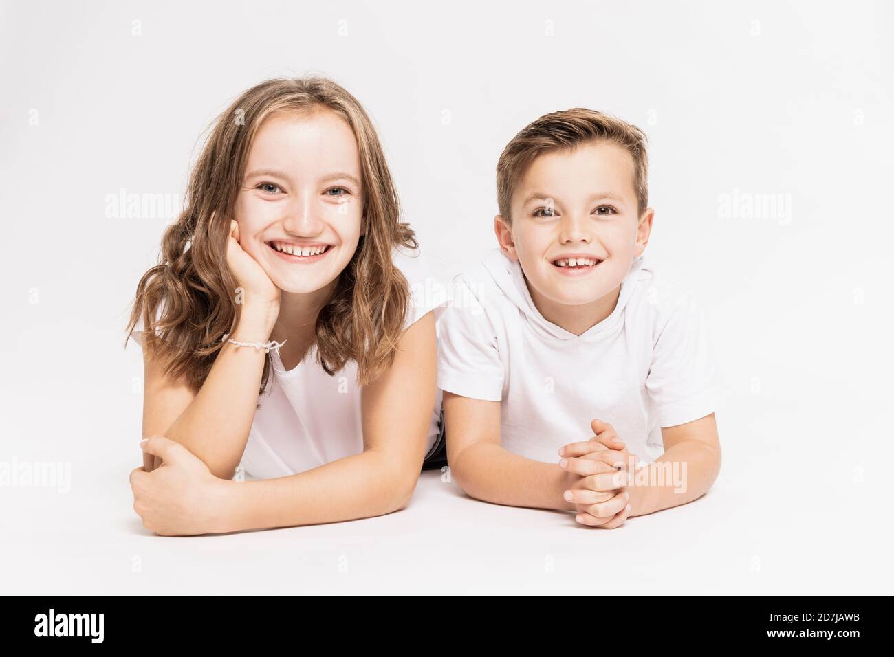 Cute smiling siblings lying on white background Stock Photo - Alamy