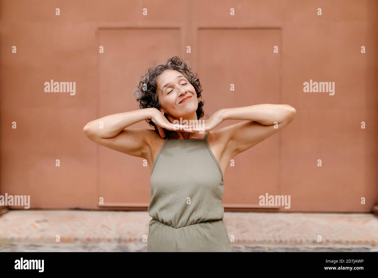 Contemplating woman with hand on standing against wall Stock Photo - Alamy