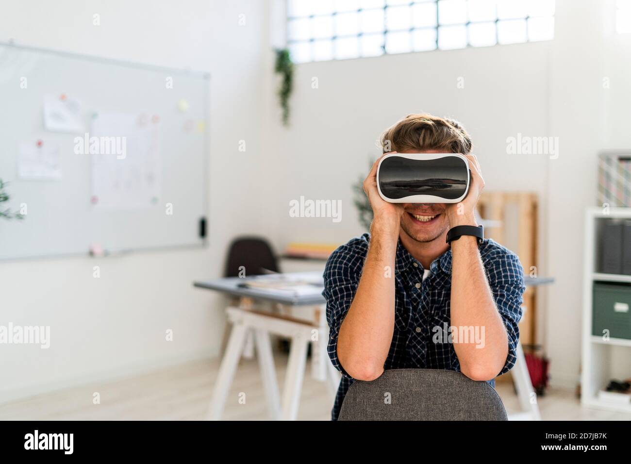 Man using visual simulator while sitting on chair at office Stock Photo ...