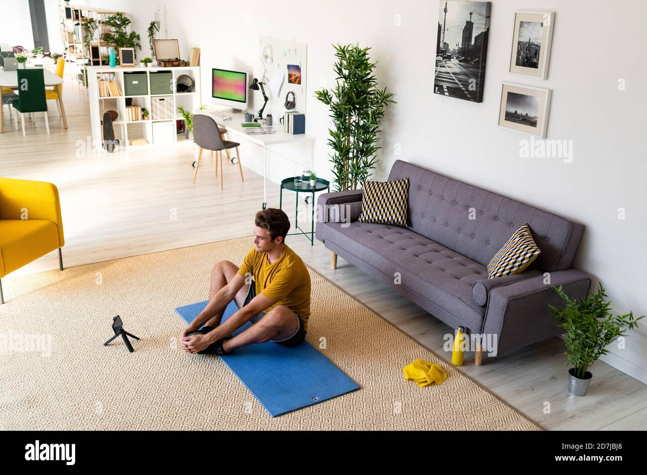 Man watching mobile phone while exercising at home Stock Photo - Alamy