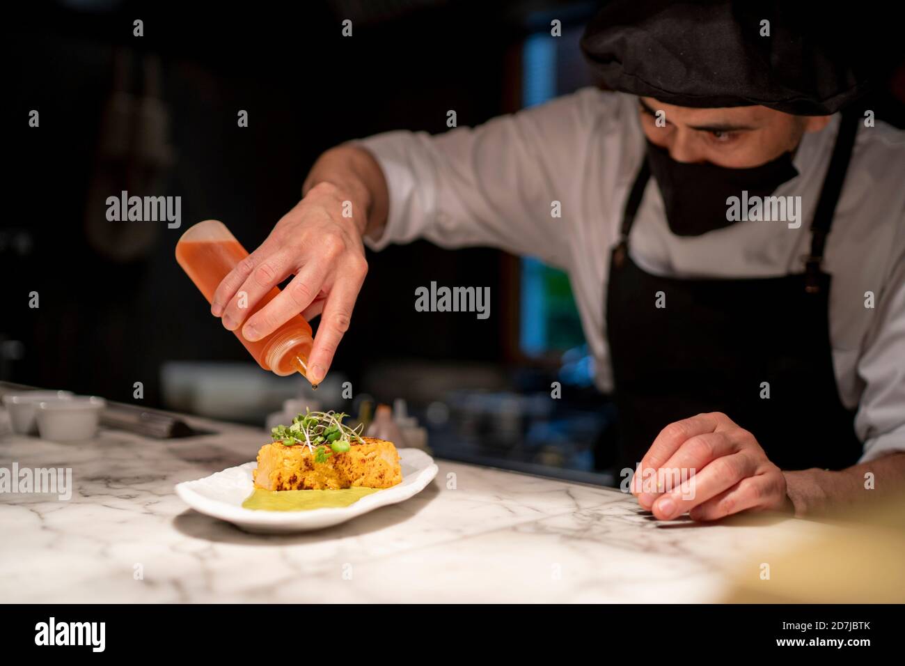 Chef wearing protective face mask while garnishing pudding standing in ...