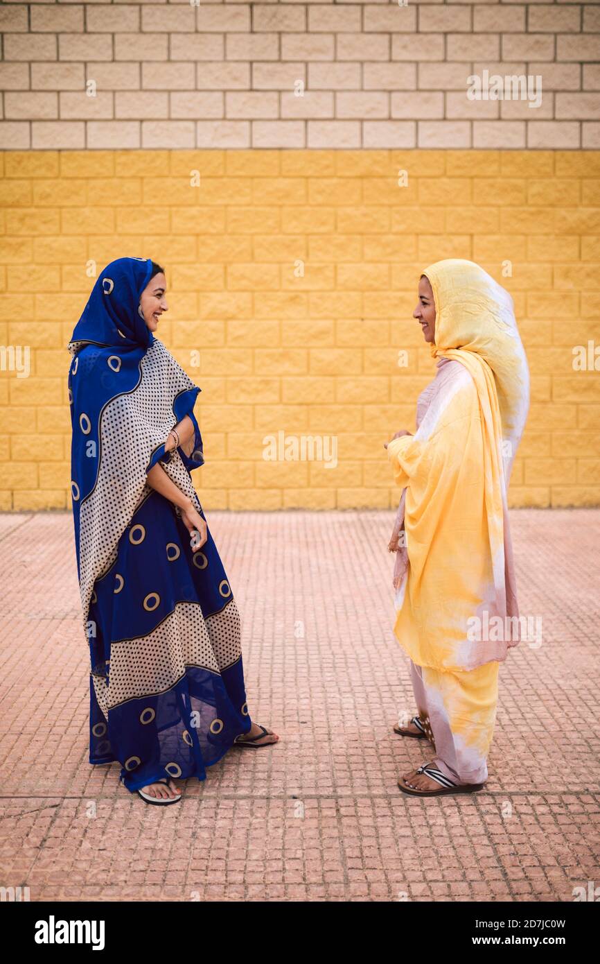 Friends talking with each other while standing by wall Stock Photo - Alamy