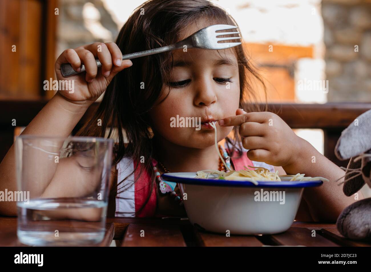Girl eating food while sitting by table at home Stock Photo - Alamy