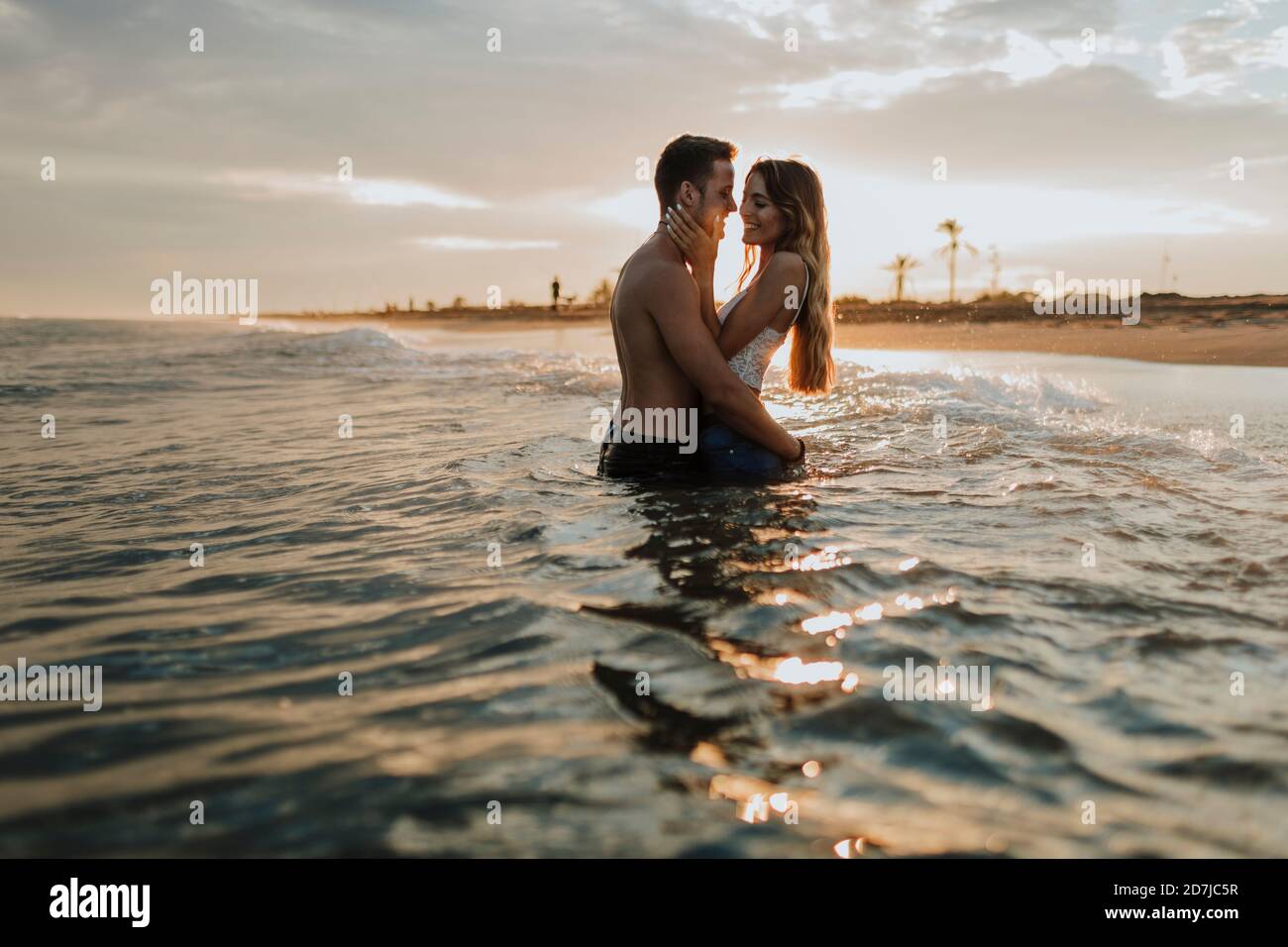 Romantic couple standing in water at beach Stock Photo - Alamy