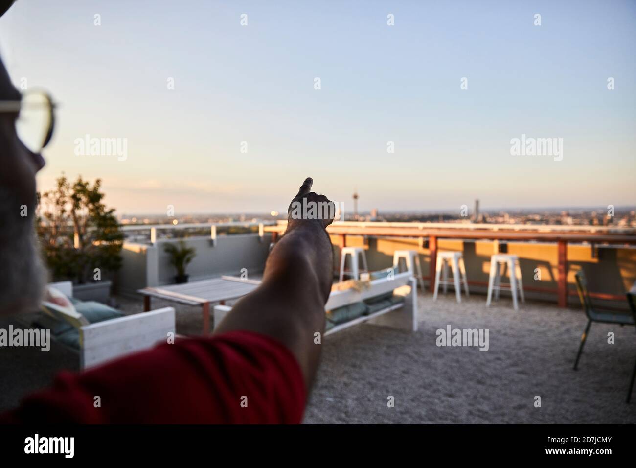 Cropped image of man pointing at clear sky from building terrace during ...