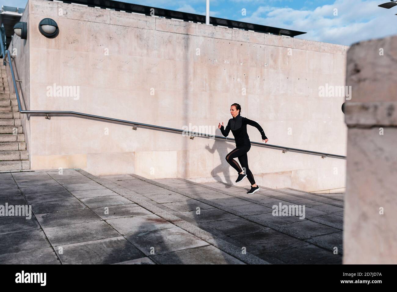 Female athlete running on steps in city Stock Photo - Alamy