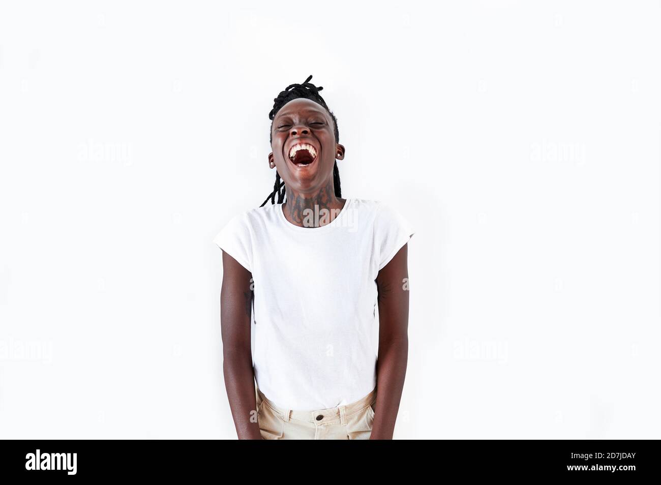 Cheerful young woman laughing while standing against white background ...