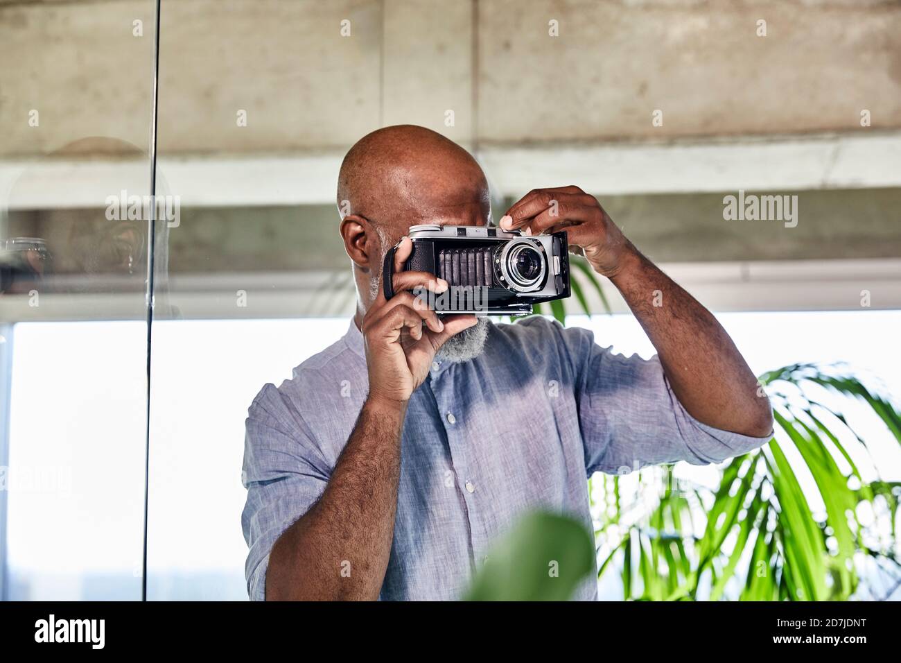 Mature man taking photo from digital camera while standing at home ...