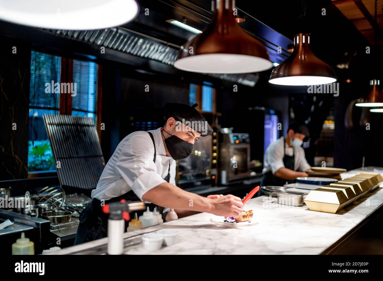 Three chefs working side by side in busy commercial kitchen Stock Photo ...