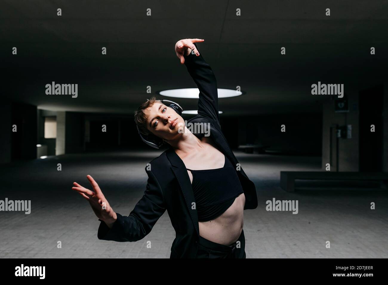 Trans young man listening music over headphones and dancing in ...