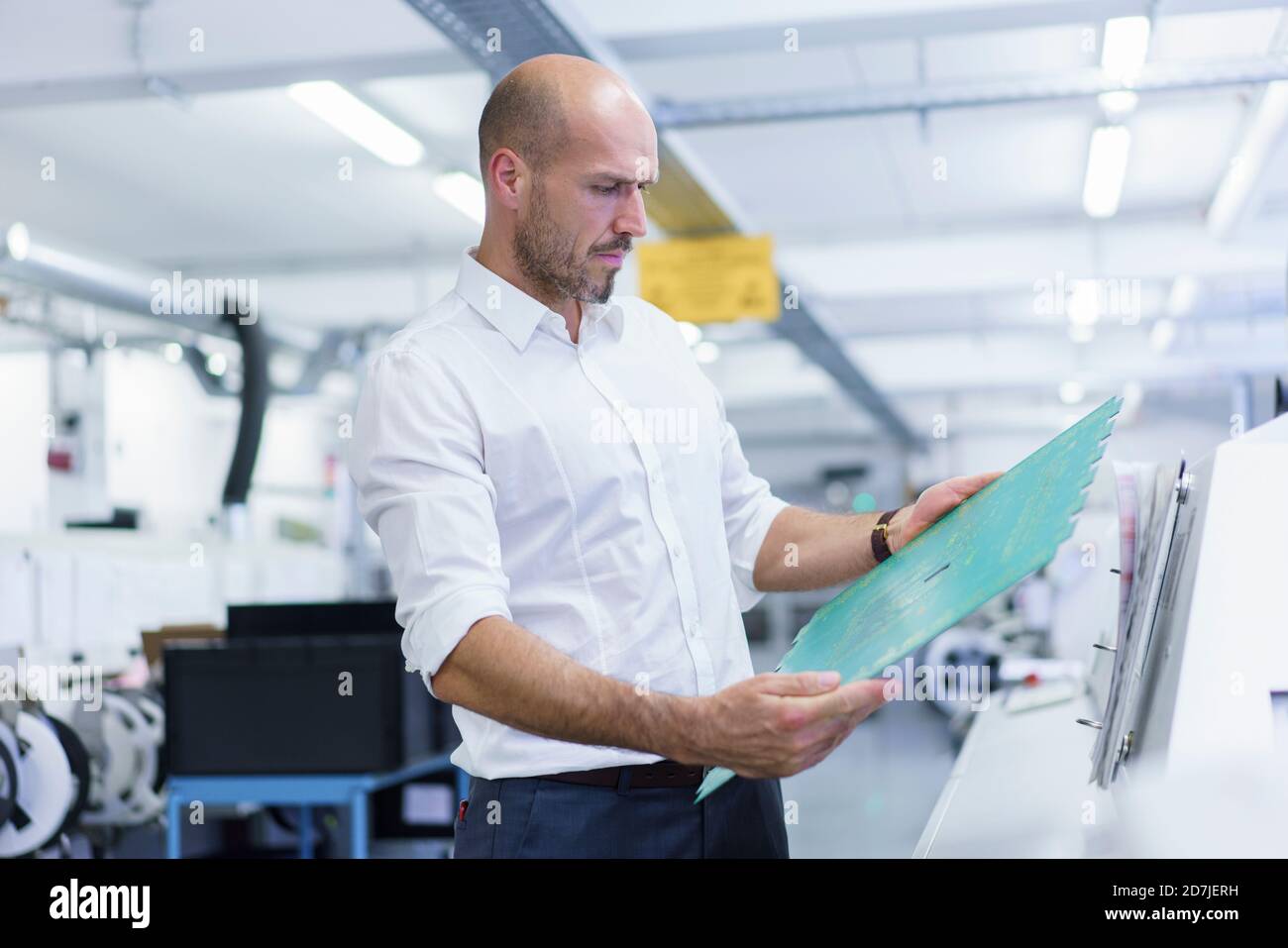 Confident mature male engineer analyzing large circuit board at ...