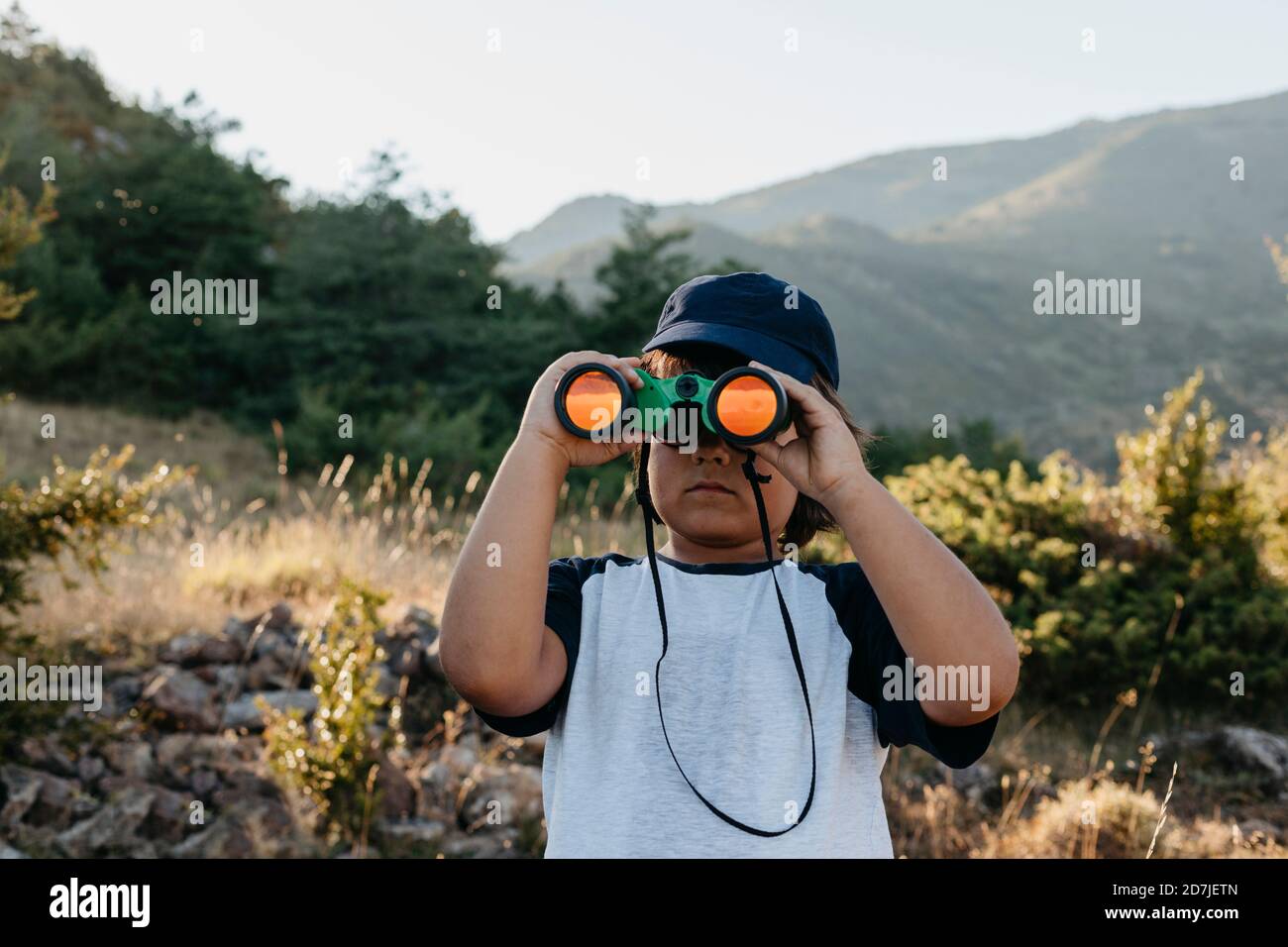 Boy using binocular while standing on mountain Stock Photo - Alamy