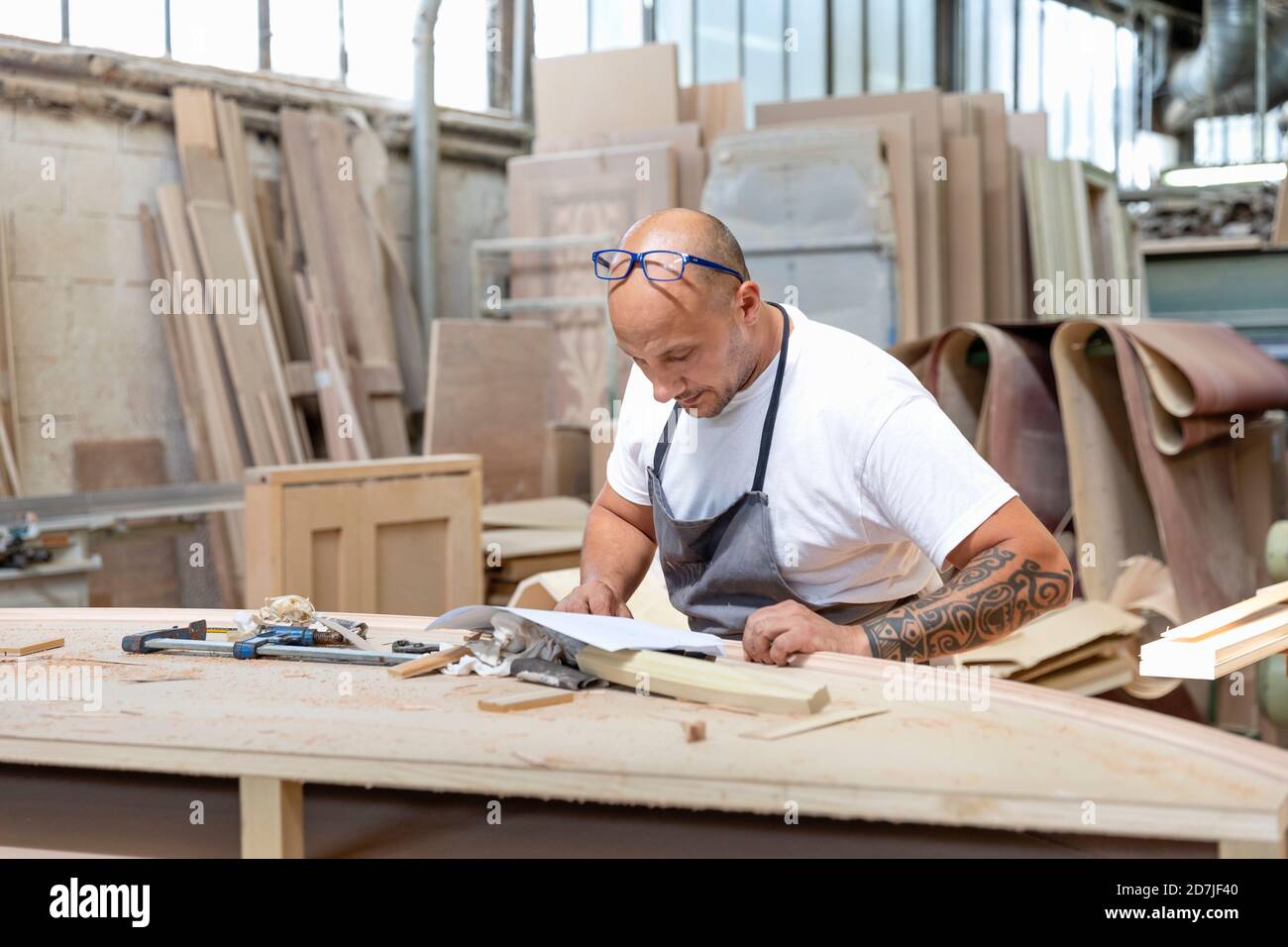 Carpenter reading design in paper while standing at workbench in ...