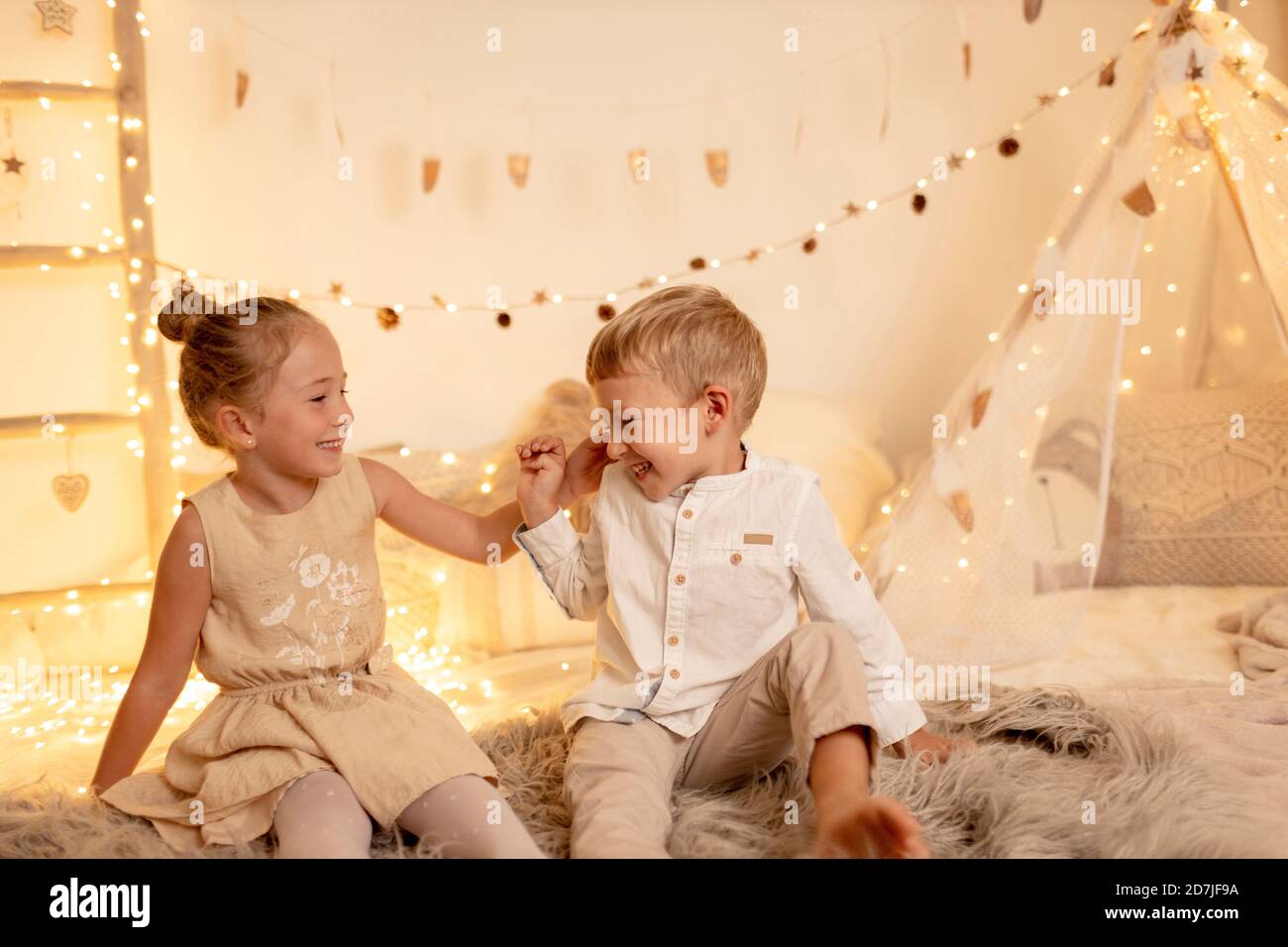 Sister pulling cheeks of brother while sitting in room Stock Photo - Alamy